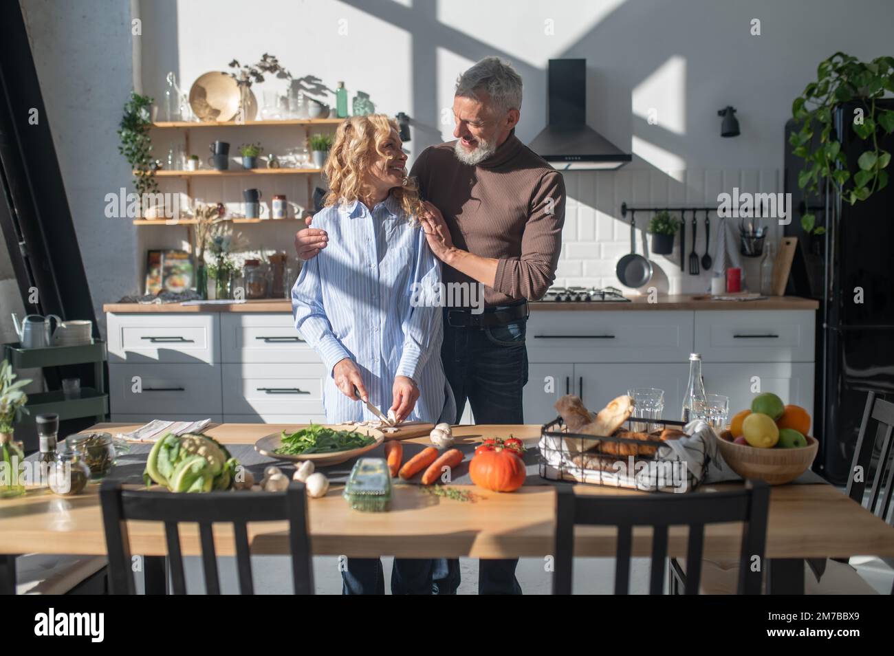 Mature couple cooking together in the kitchen and looking happy Stock ...