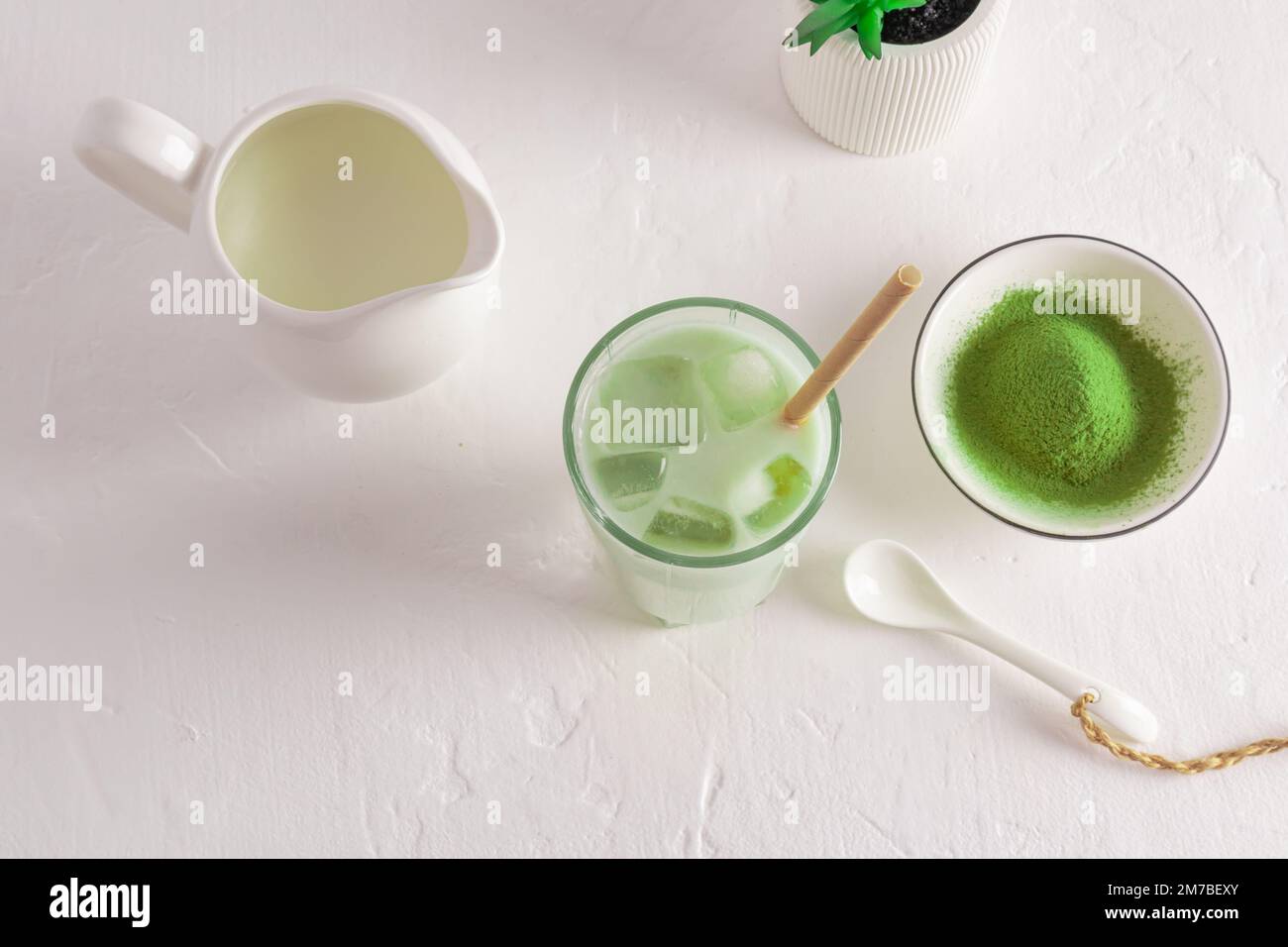 green healthy matcha latte tea with ice cubs on a white table with a ...