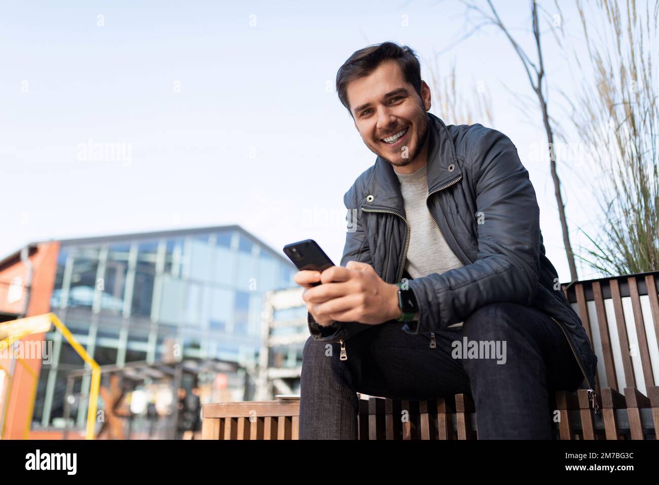 young man in jacket with phone outside Stock Photo - Alamy