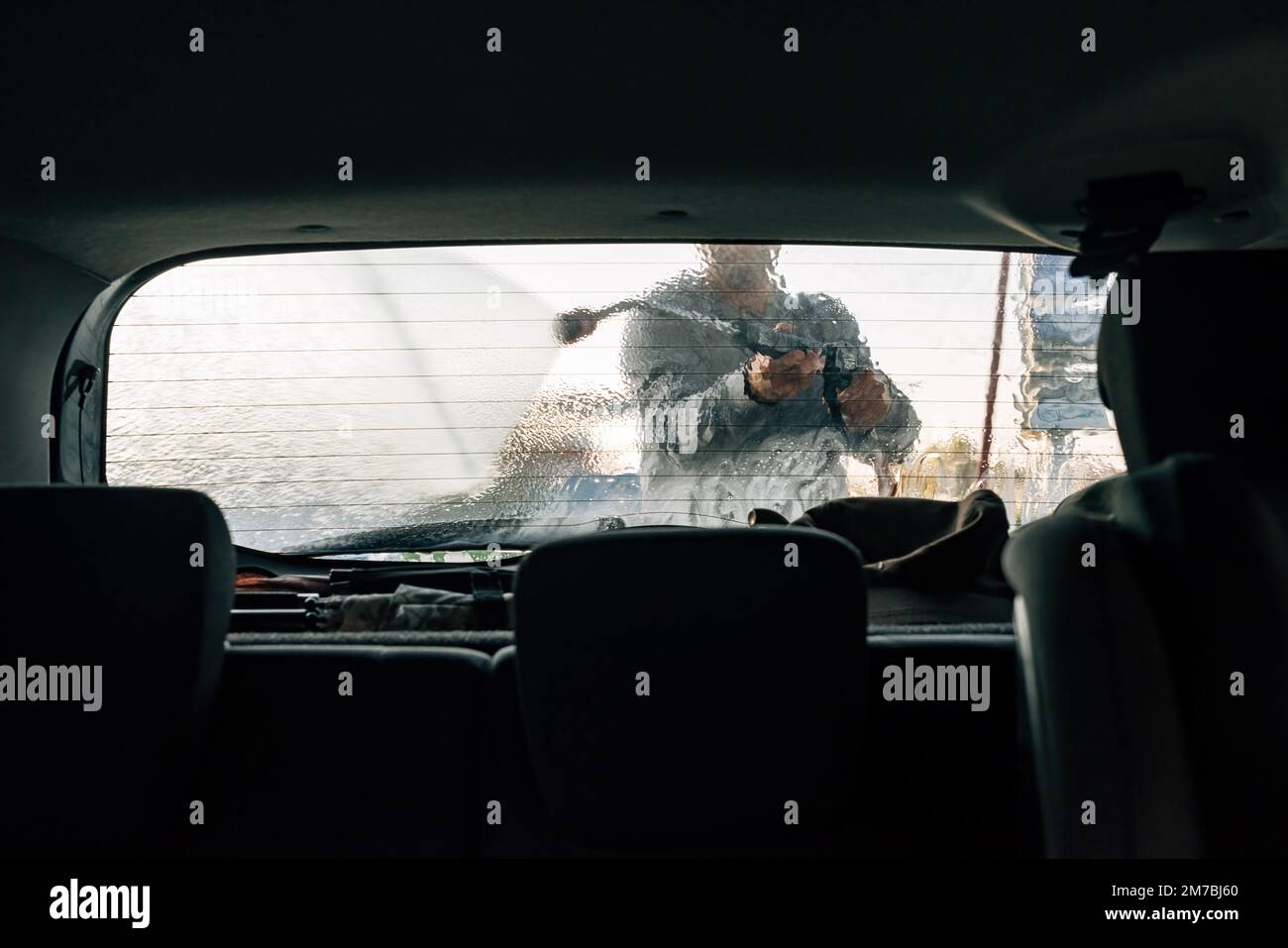 Man washing car with water gun in carwash self-service. Soap sud, wax ...