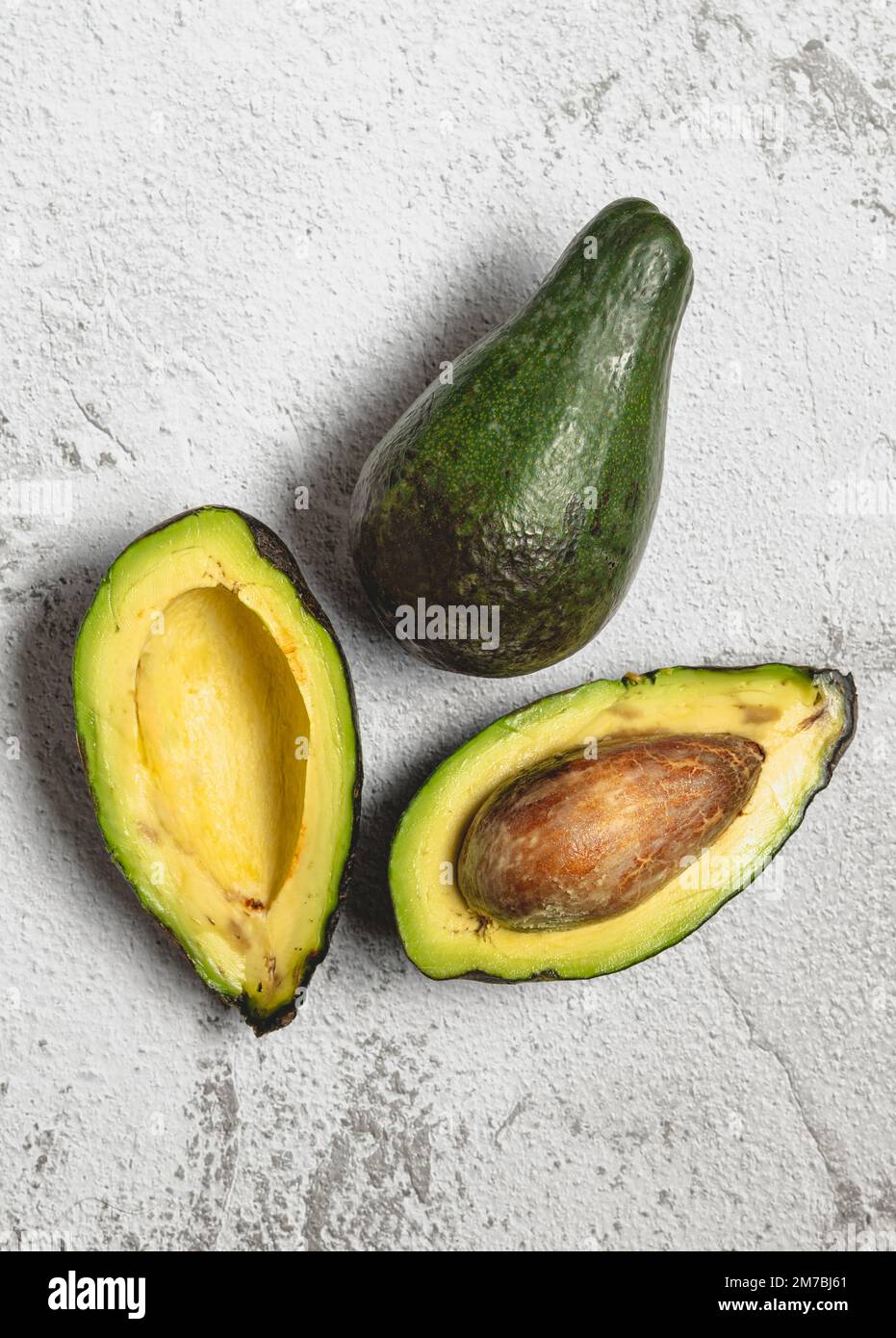 Top view of both cut and whole ripe avocado on white stone table Stock ...