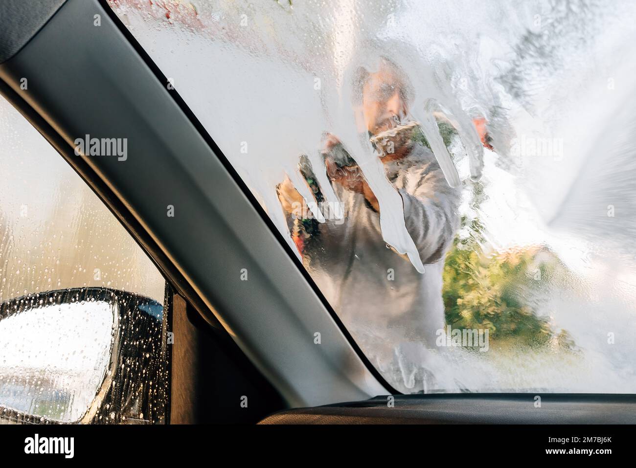 Man washing car with water gun in carwash self-service. Soap sud, wax ...