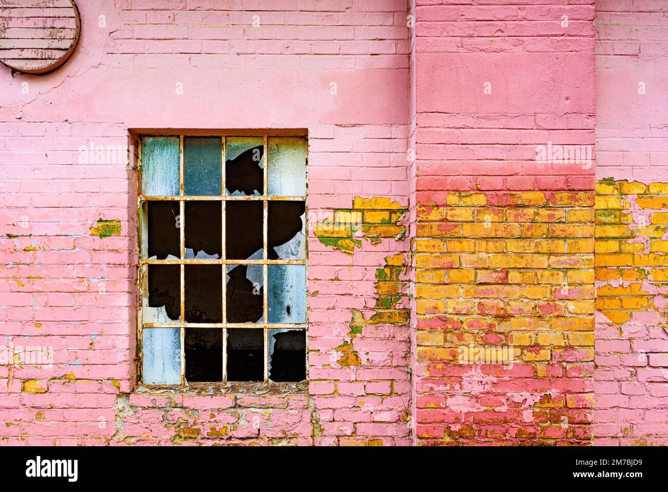 Old grid windows with broken glass on exterior wall of an old abandoned ...
