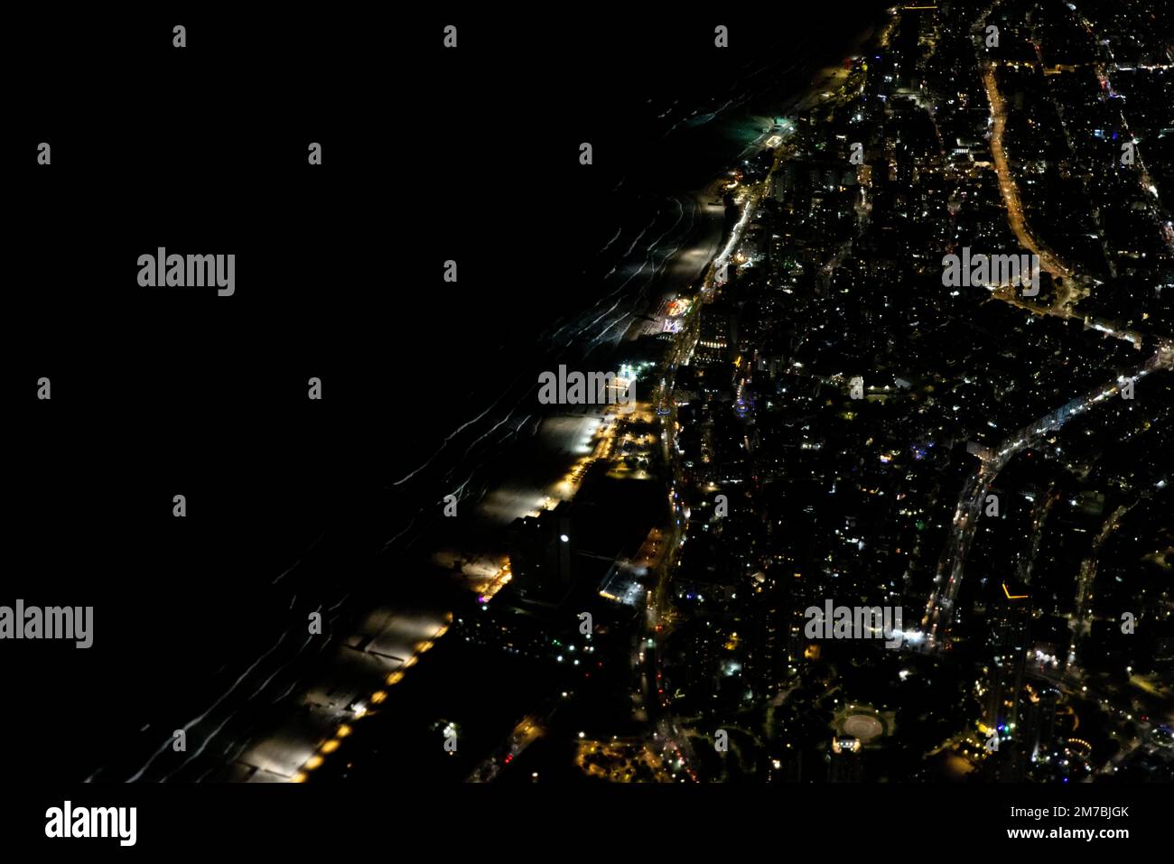 A bird's eye view of city lights illuminating the dark coastline ...