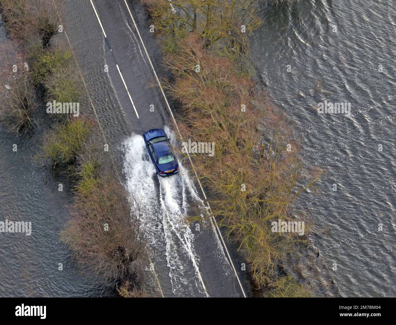 A car travels along the road as the Welney wash fills with floodwater ...