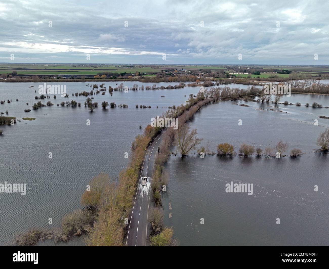 A truck travels along the road as the Welney wash fills with floodwater ...