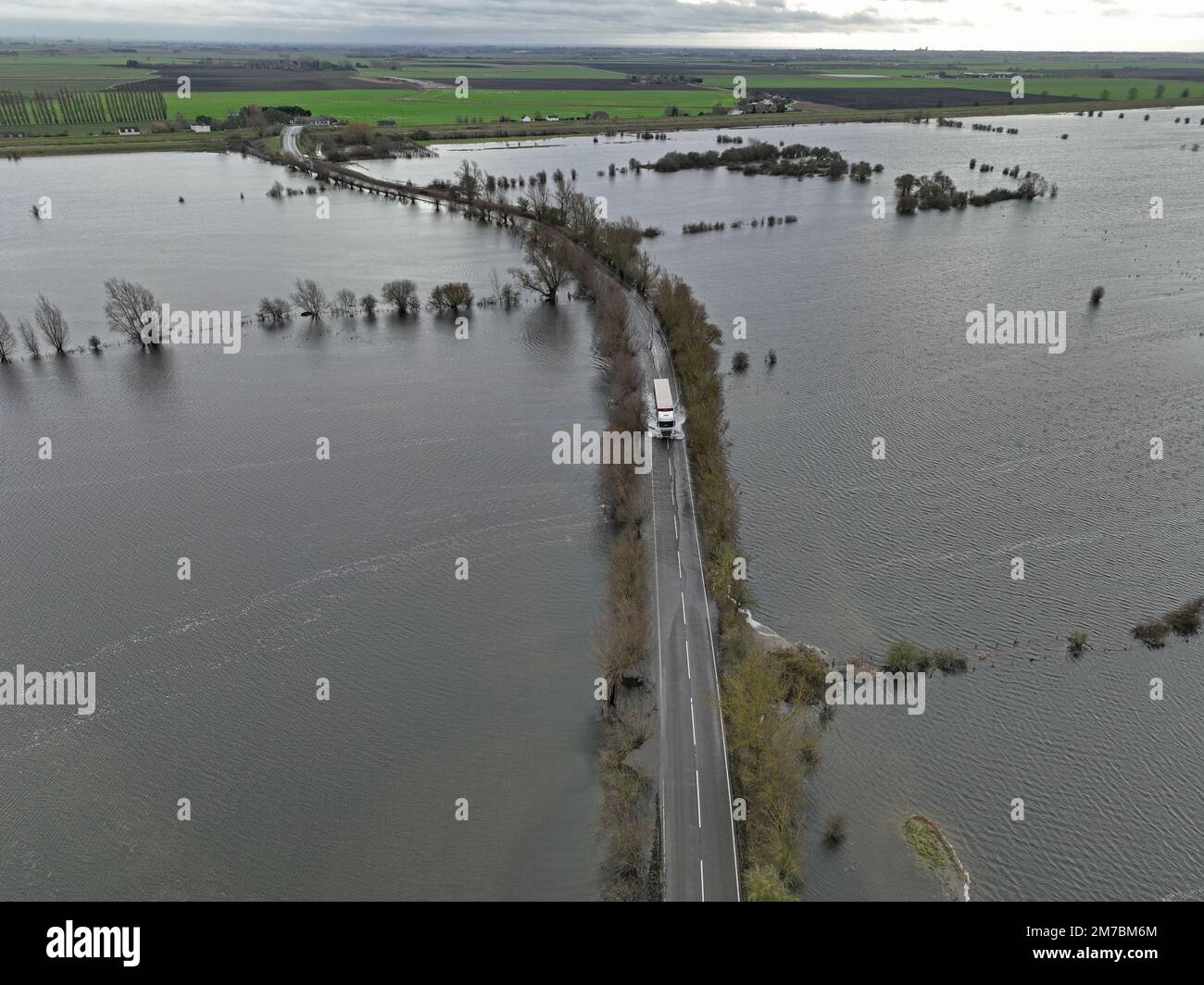 A lorry travels along the road as the Welney wash fills with floodwater ...