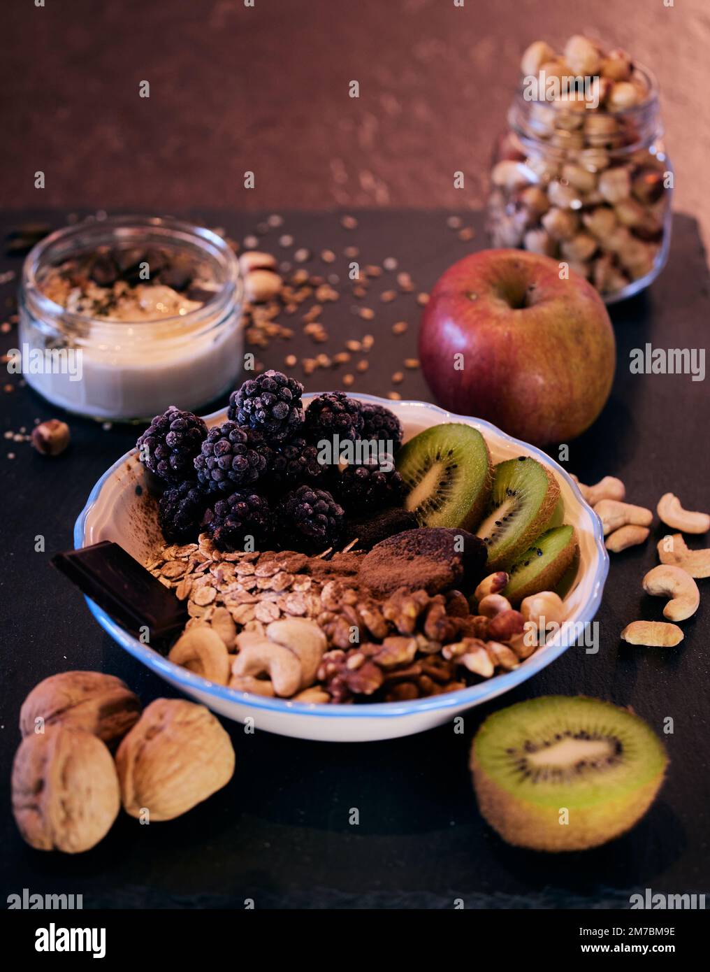 A vertical shot of a healthy bowl of fruits and oats on a messy table ...