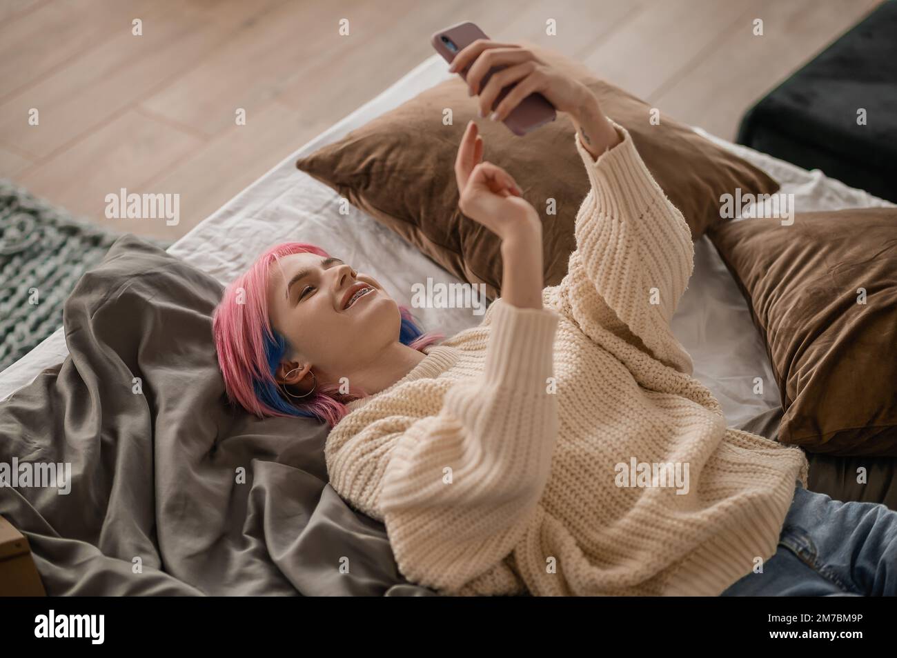 Contented girl using her cellphone in the bedroom Stock Photo - Alamy