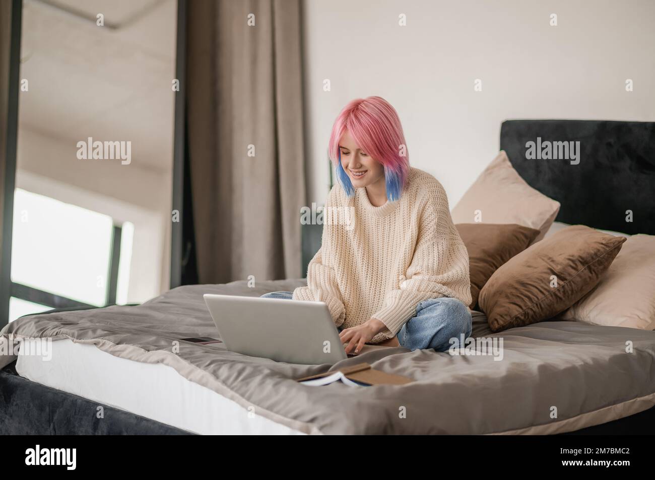 Contented pink-haired girl using her portable computer Stock Photo - Alamy