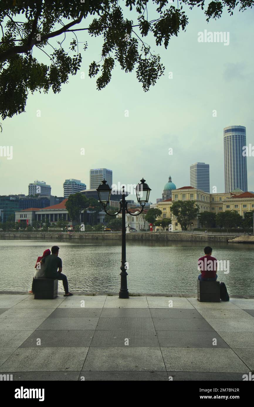 A vertical shot of a couple and a man, each sitting on either side of a ...