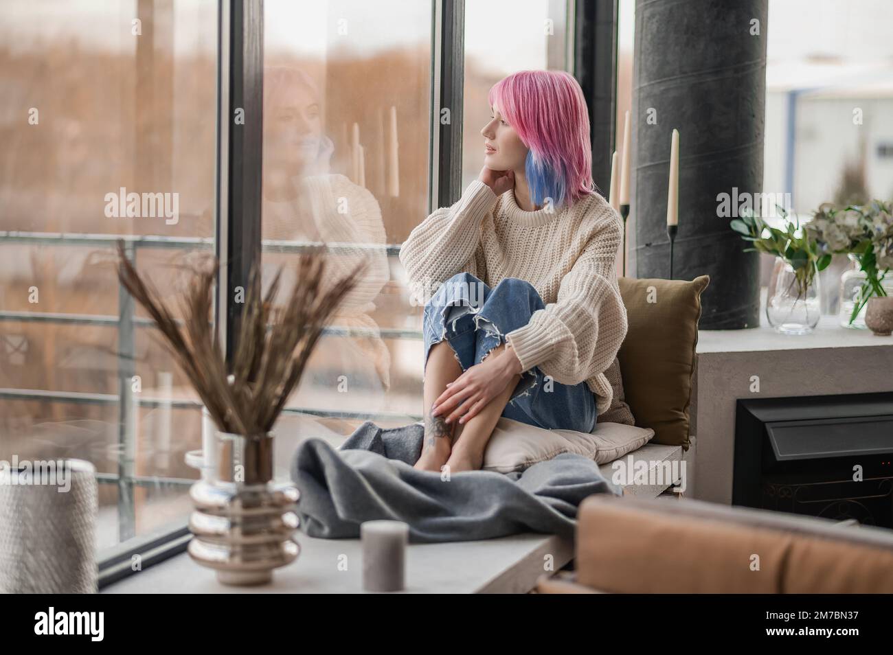 Cute tranquil thoughtful girl seated on the window ledge Stock Photo ...