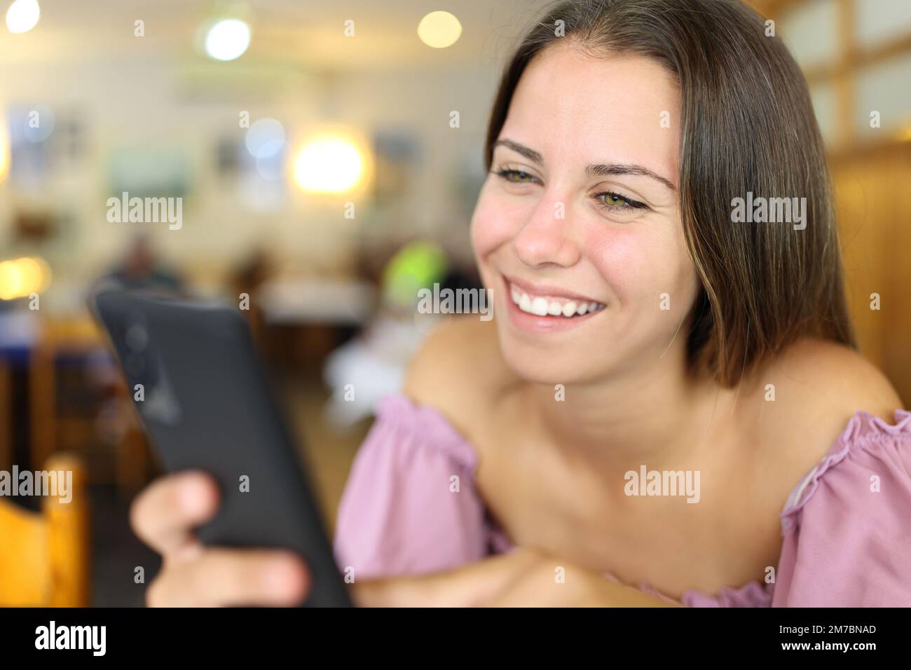 Happy teen using cell phone in a restaurant interior Stock Photo - Alamy