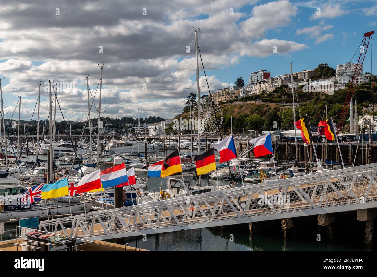 A view across Torquay Harbour showing flags from many countries. In the ...