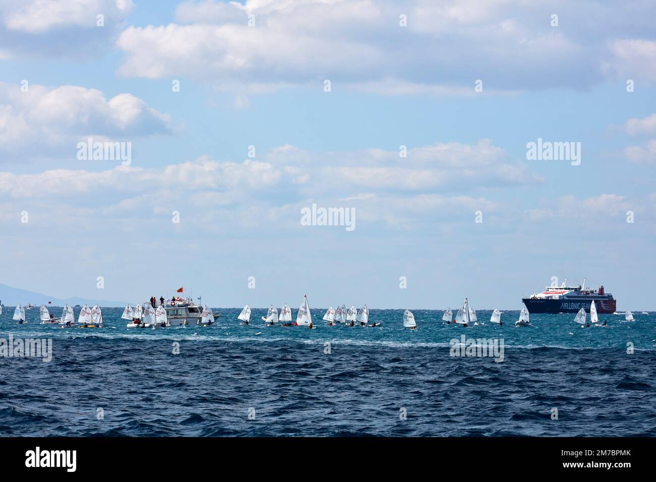 Little sail boats in a row at open water training and big ferry ship in ...