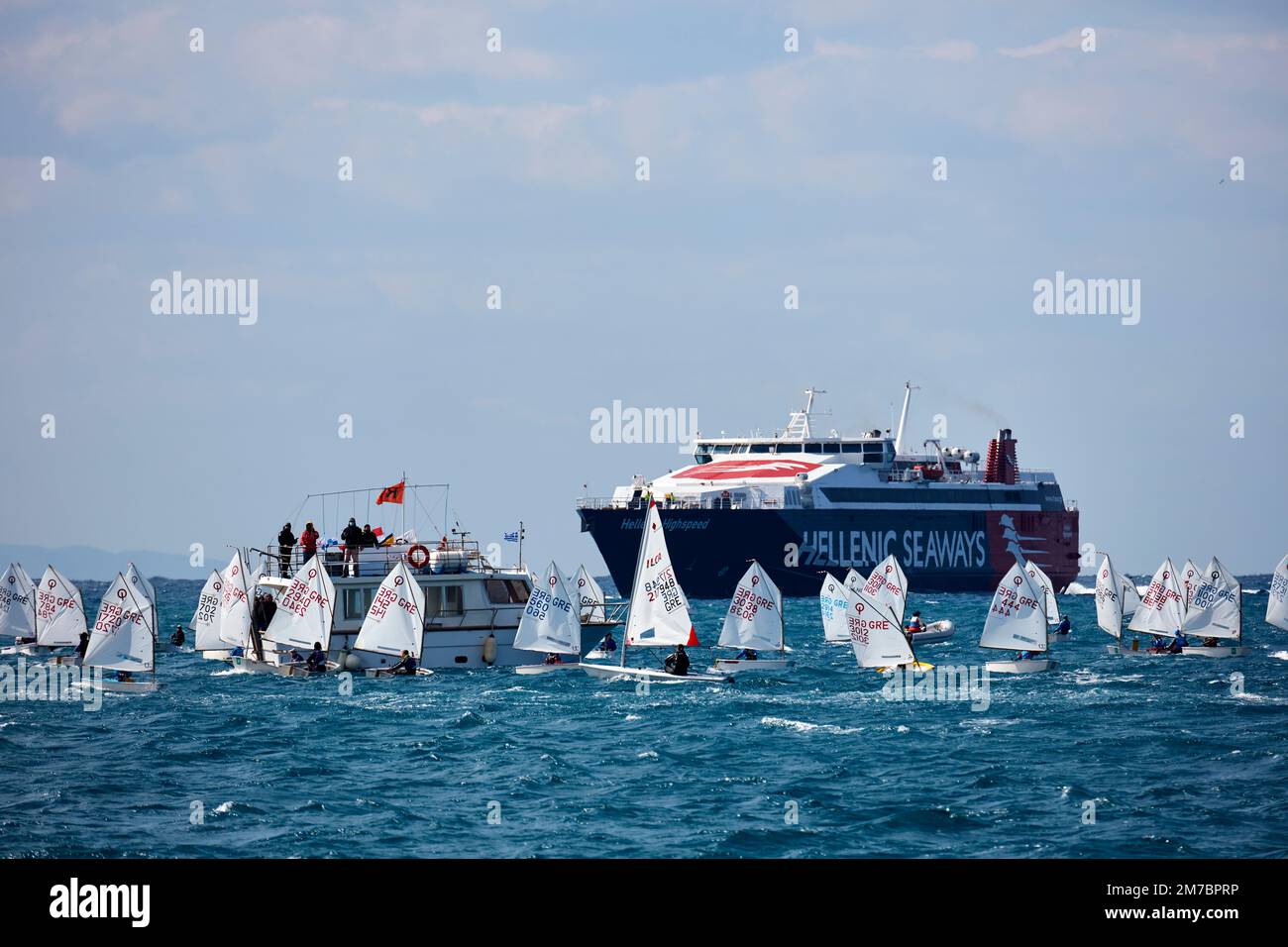 Little sail boats in a row at open water training and big ferry ship in ...