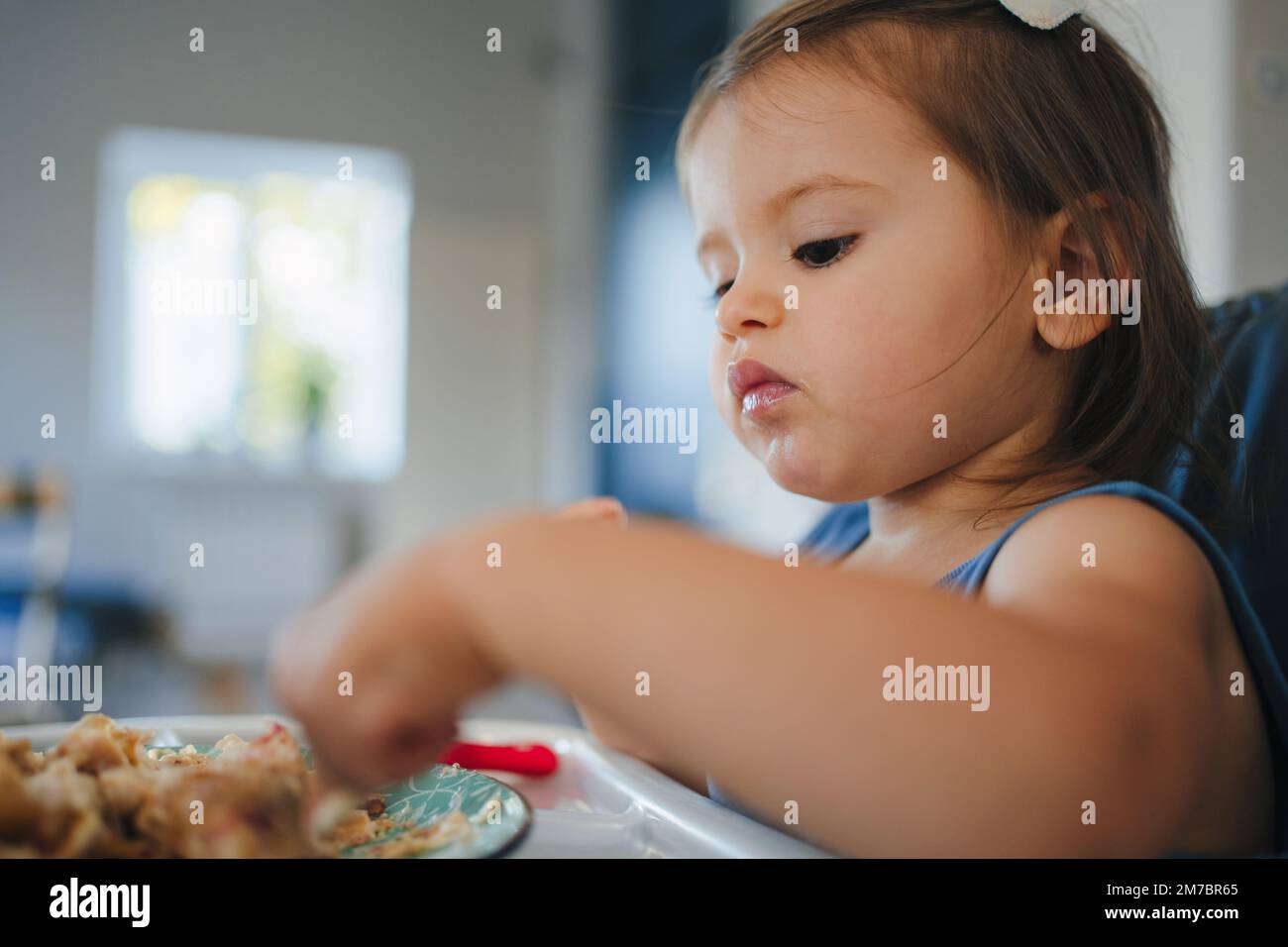 Happy baby girl eating with finger solid food. Baby led weaning self ...