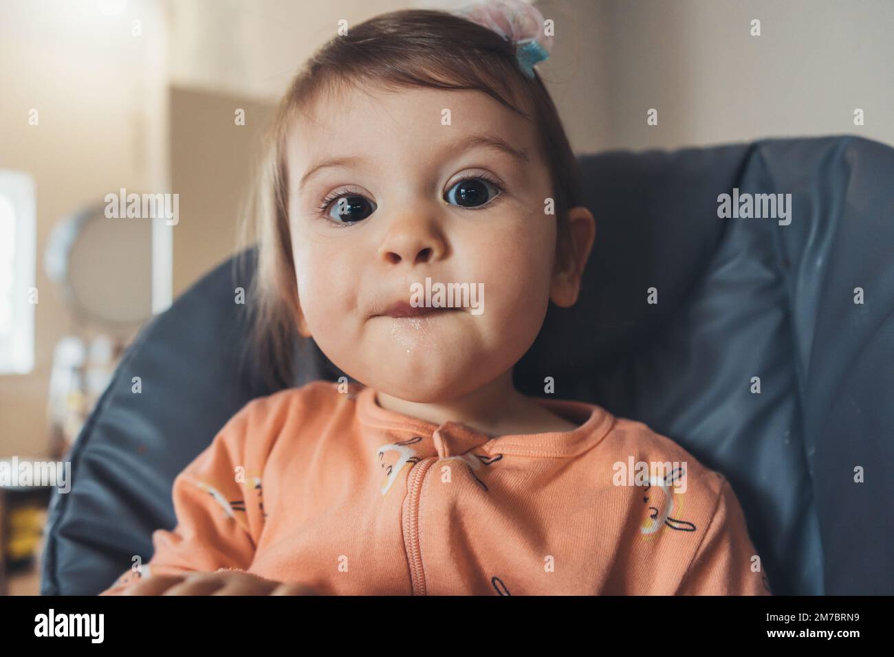 Cute little baby girl sitting on a high chair. Cute little girl in a ...