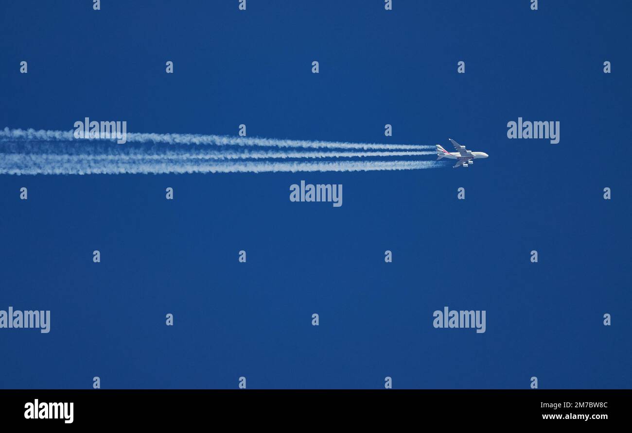 A white aircraft at a distance and contrails in clear blue sky Stock ...