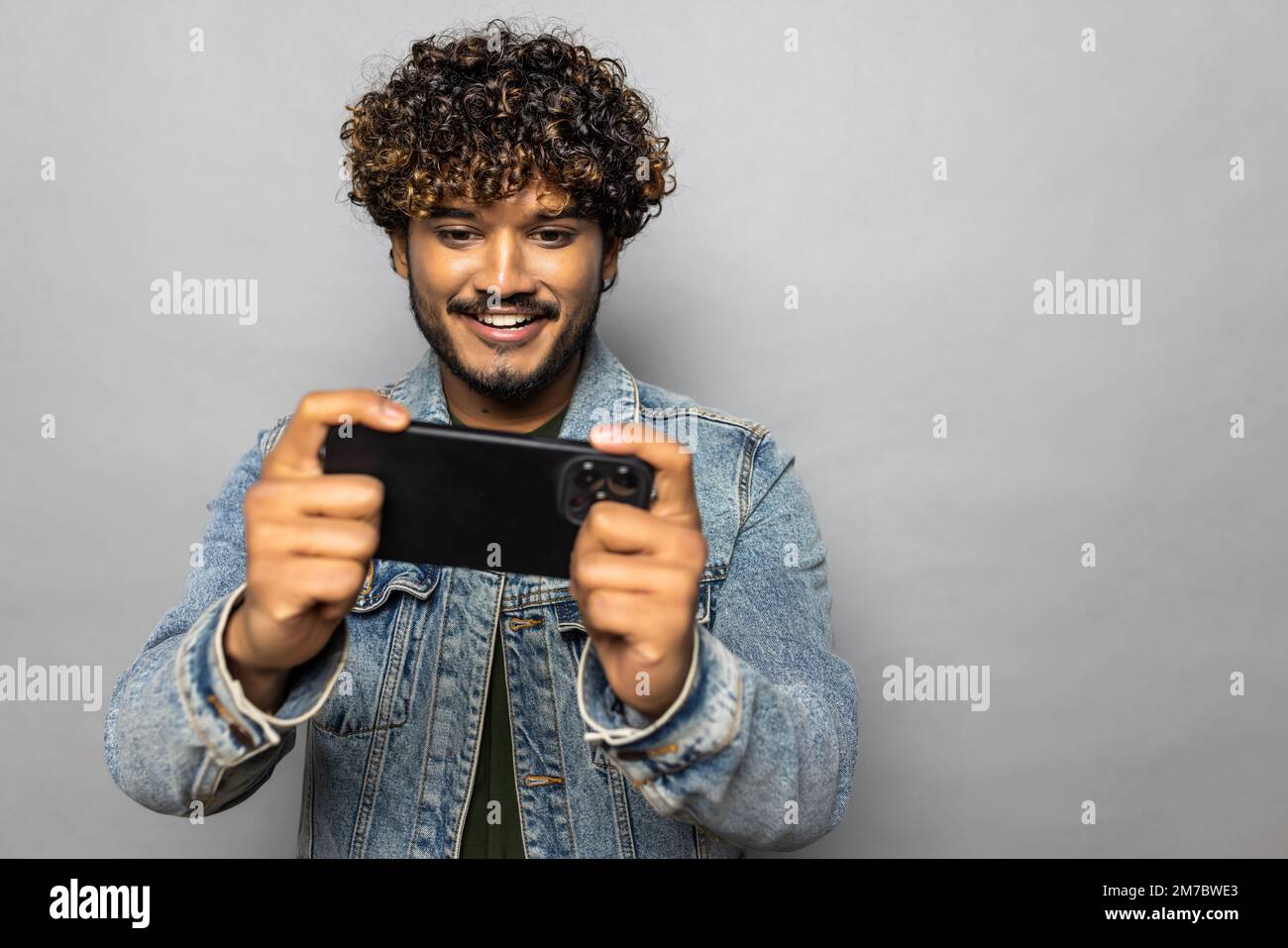 technology, gaming and people concept - happy indian man playing game ...