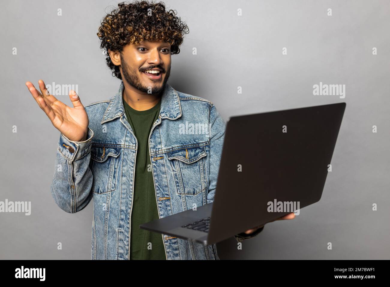 Side view young IT Indian man hold use work on laptop talk by video ...