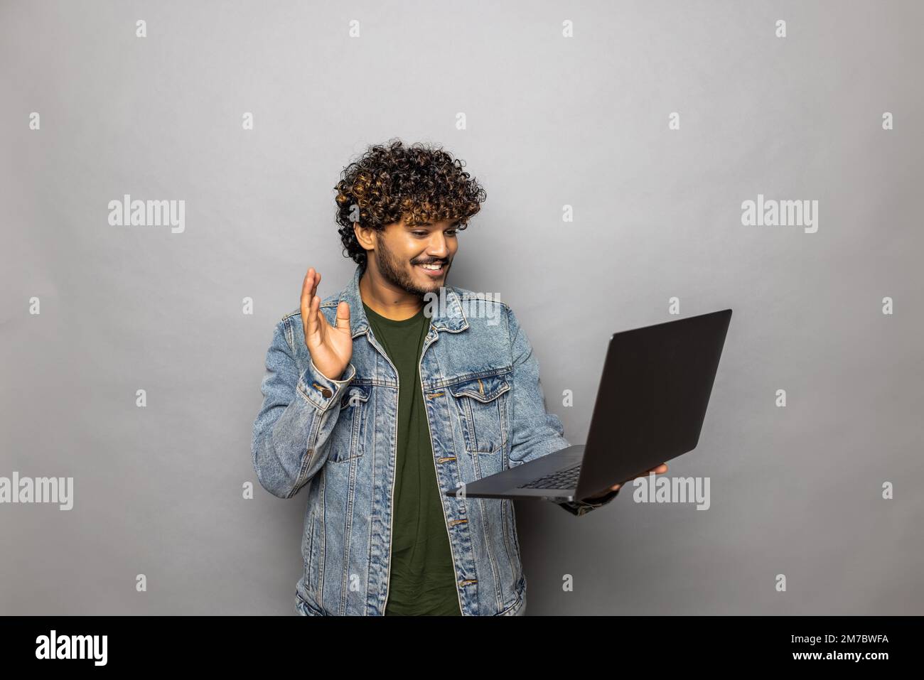Side view young IT Indian man hold use work on laptop talk by video ...