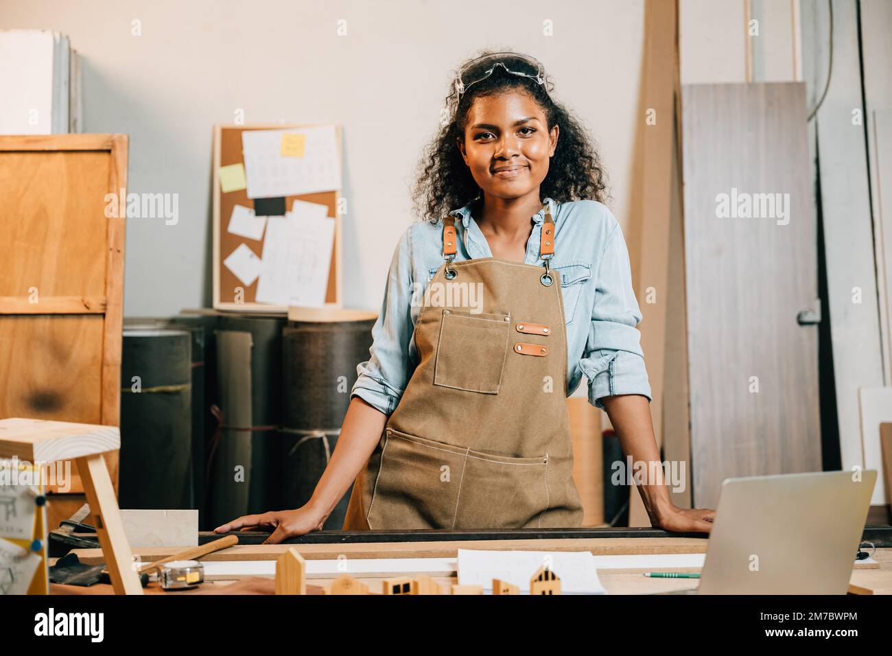 black woman carpenter standing on workspace table at workshop against ...