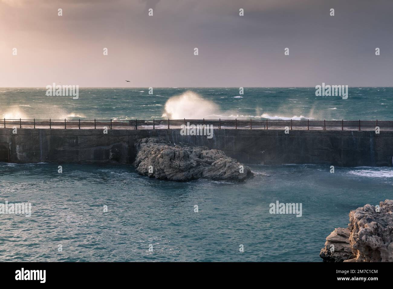 Dramatic landscape with splashing waves on stormy sea under cloudy sky ...