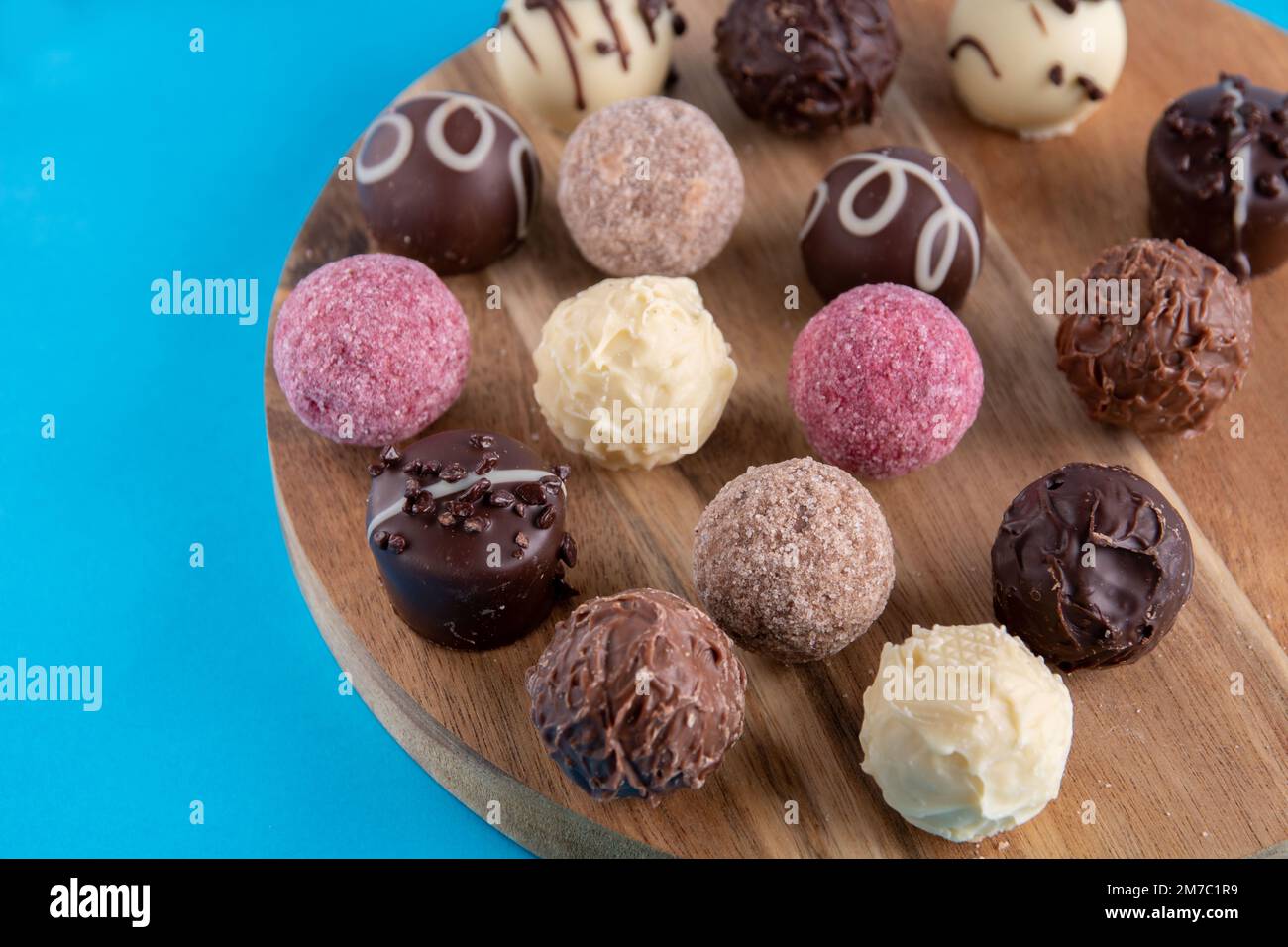 photo of lots of delicious chocolates lying on a round wooden board on ...