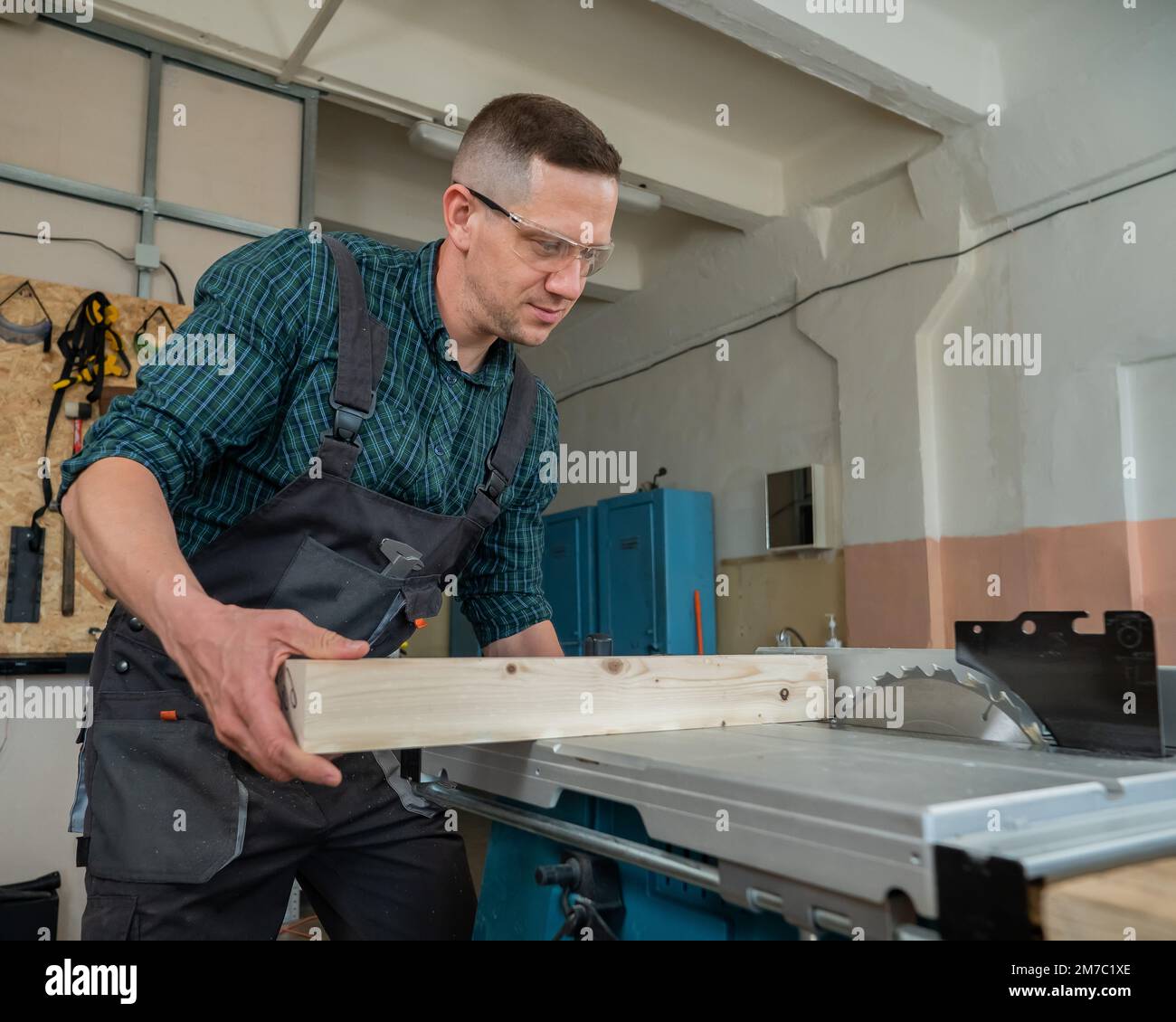 The carpenter cuts a wooden board on a circular machine Stock Photo - Alamy