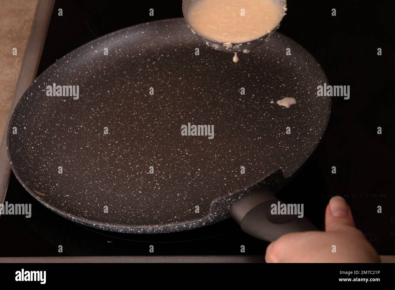 Close-up photo of a hot frying pan and a ladle with pancake batter ...