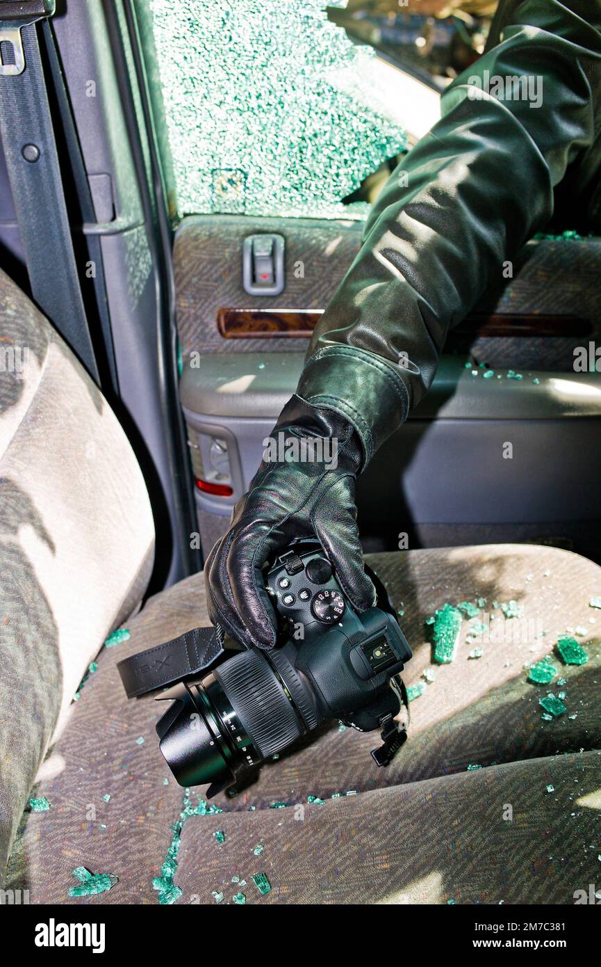 thief steals a camera from a car through a broken window pane Stock ...