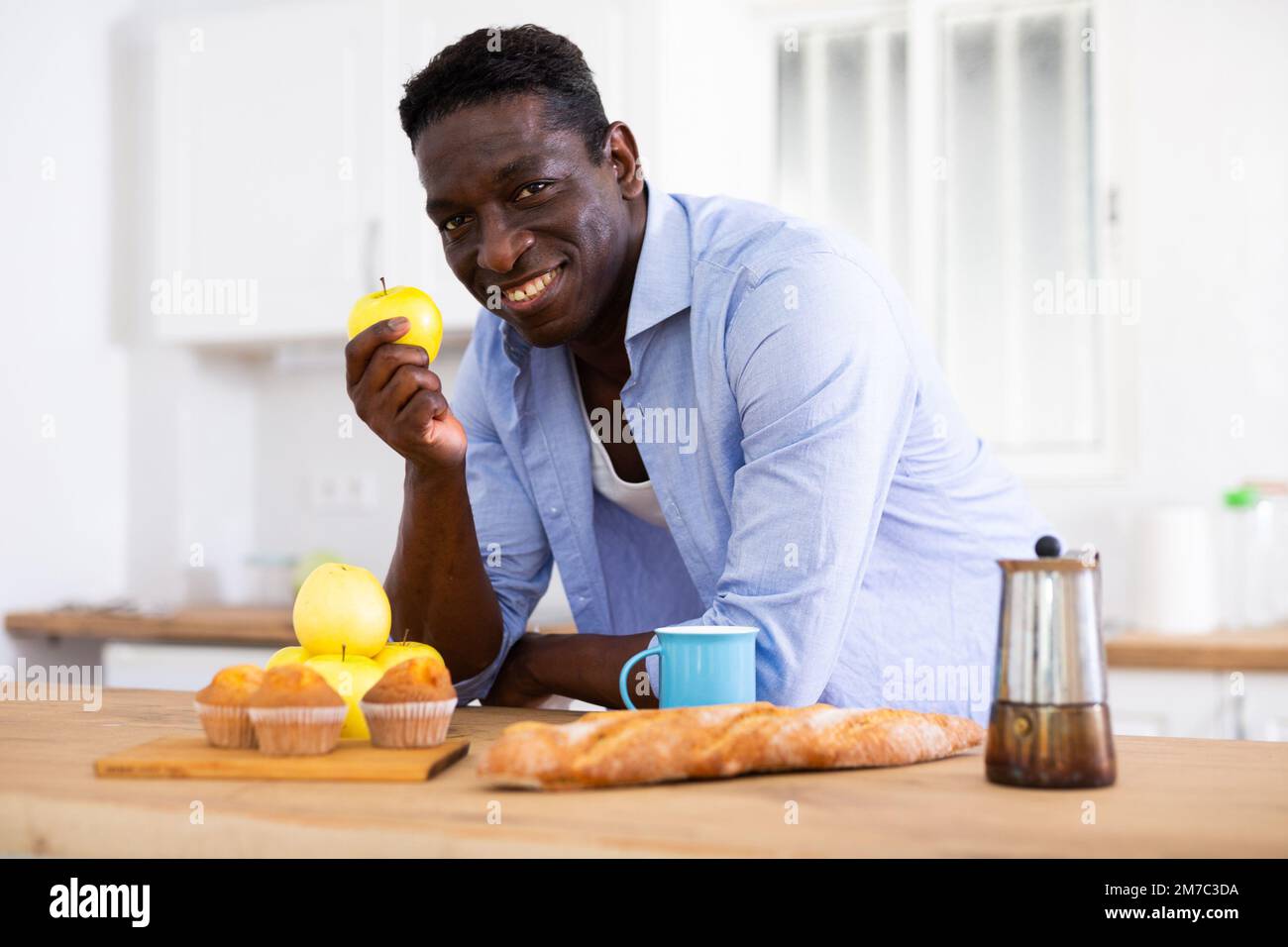 Positive man eating apple at home Stock Photo - Alamy