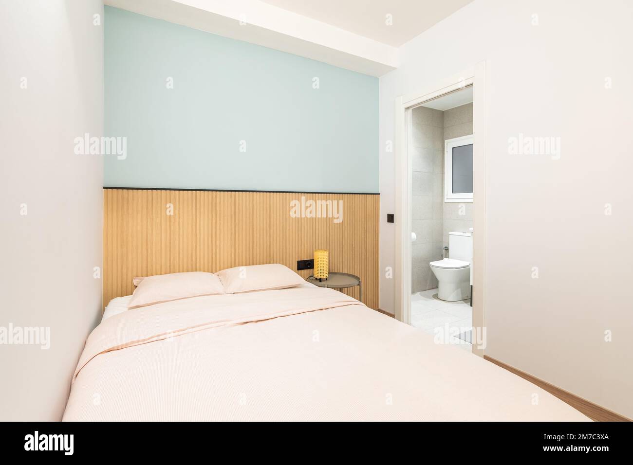 Double bed against a shallow niche with a blue wall and wooden decor ...