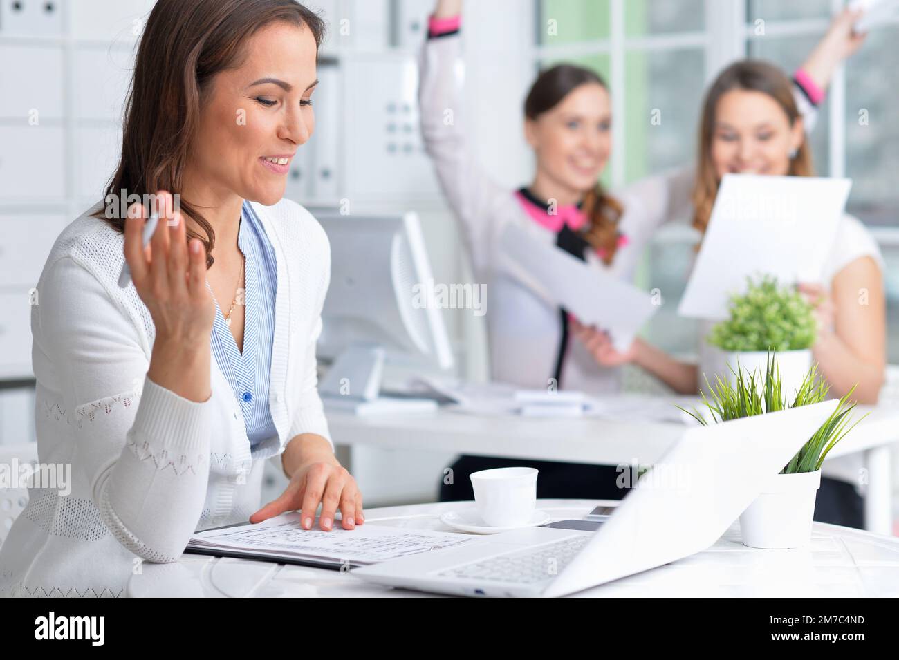 young women sit at the table and work in a modern office Stock Photo ...