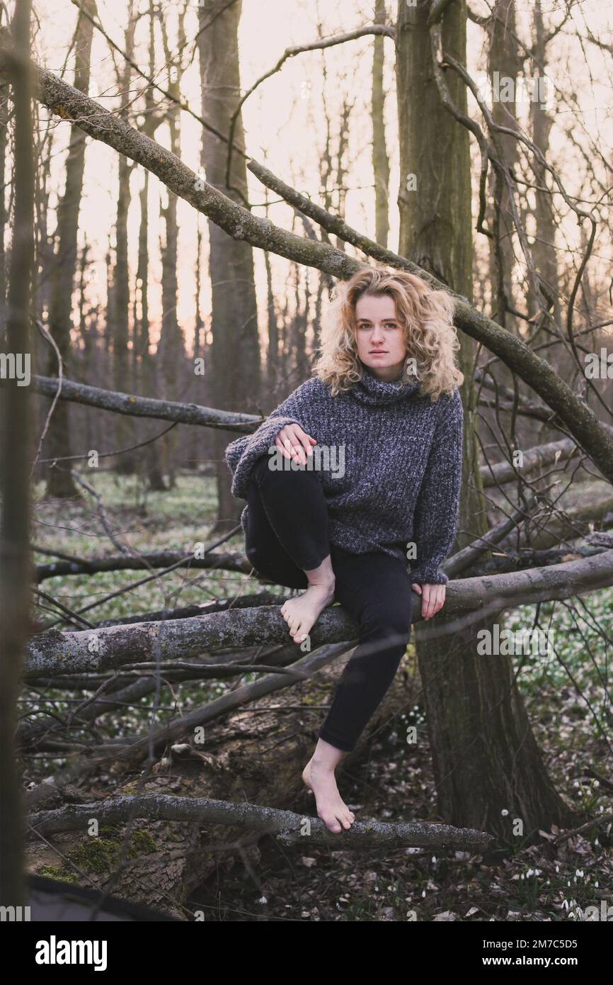 Barefoot woman sitting on fallen tree scenic photography Stock Photo - Alamy