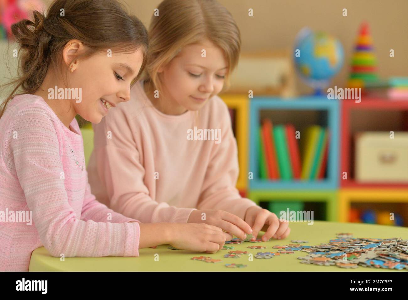 little girls collecting puzzle pieces while sitting at table Stock ...