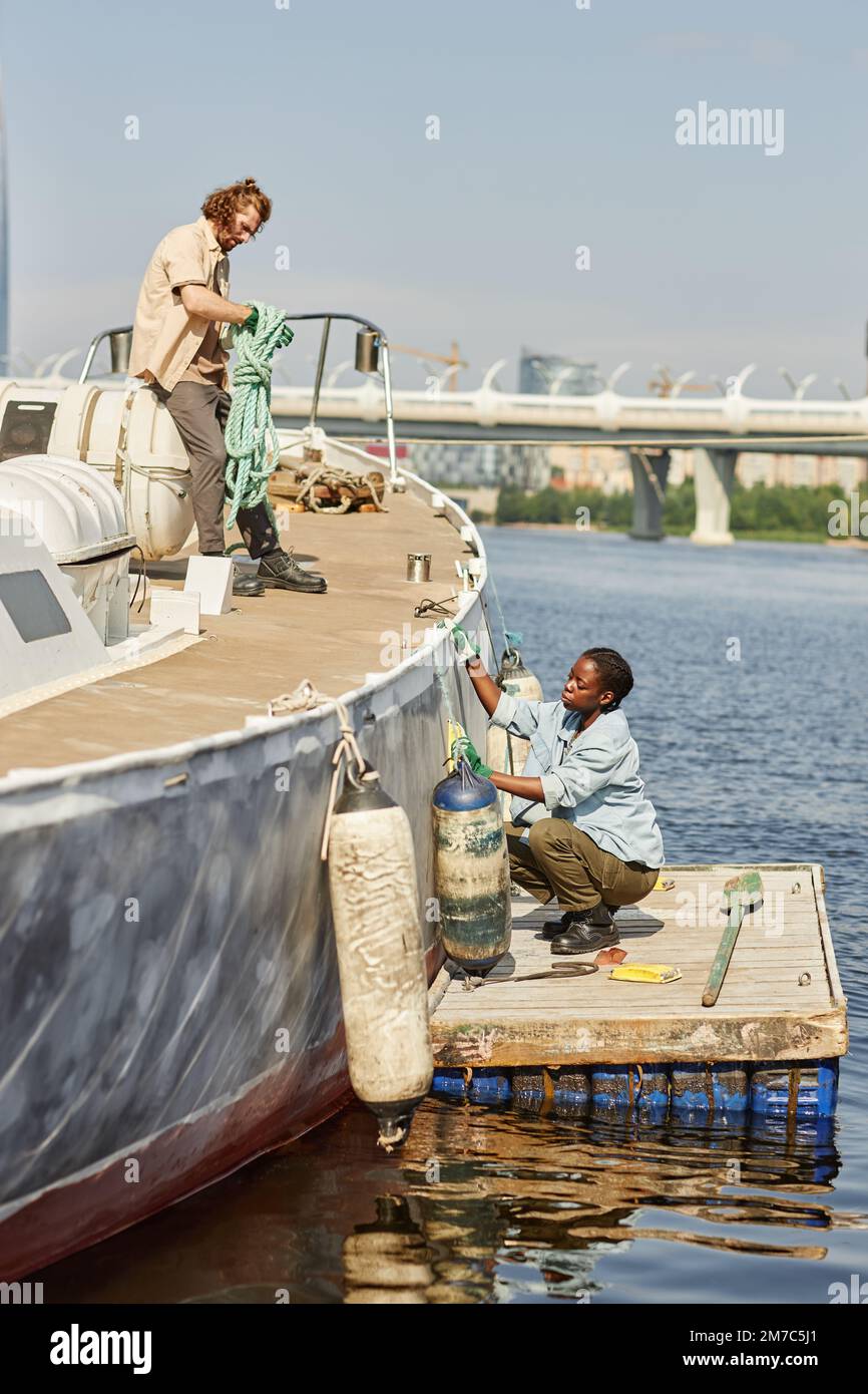 Vertical portrait of two sailors, man and woman working on boat in ...