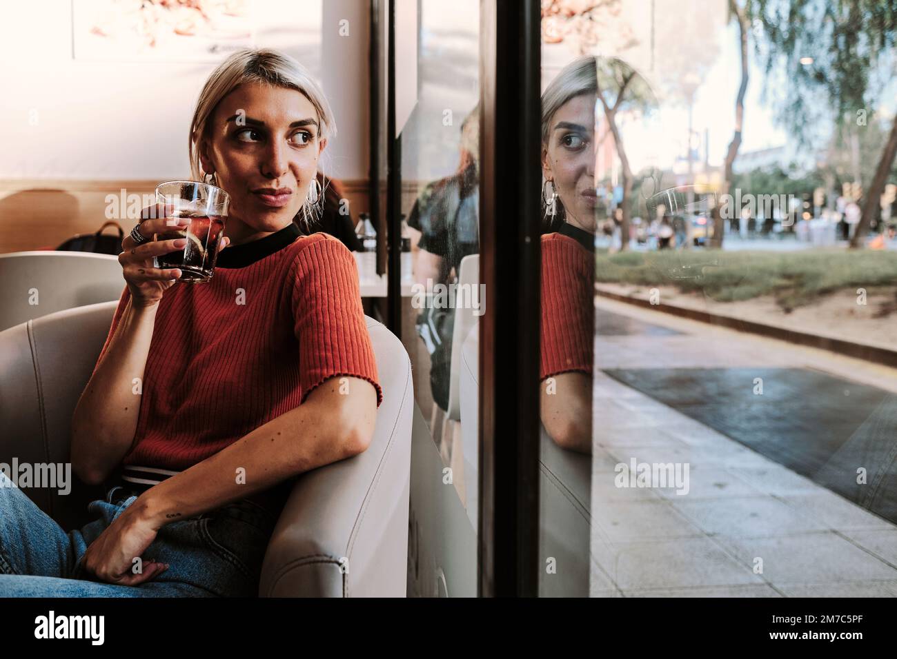 Woman looking out window while drinking a beverage in a restaurant ...