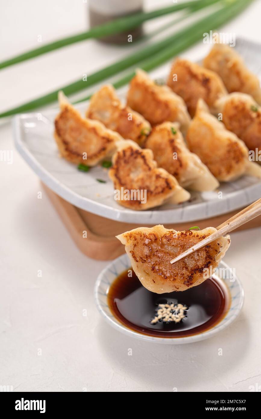 Taiwanese and Japanese Pan-fried gyoza dumpling jiaozi food in a plate with soy sauce on white ...