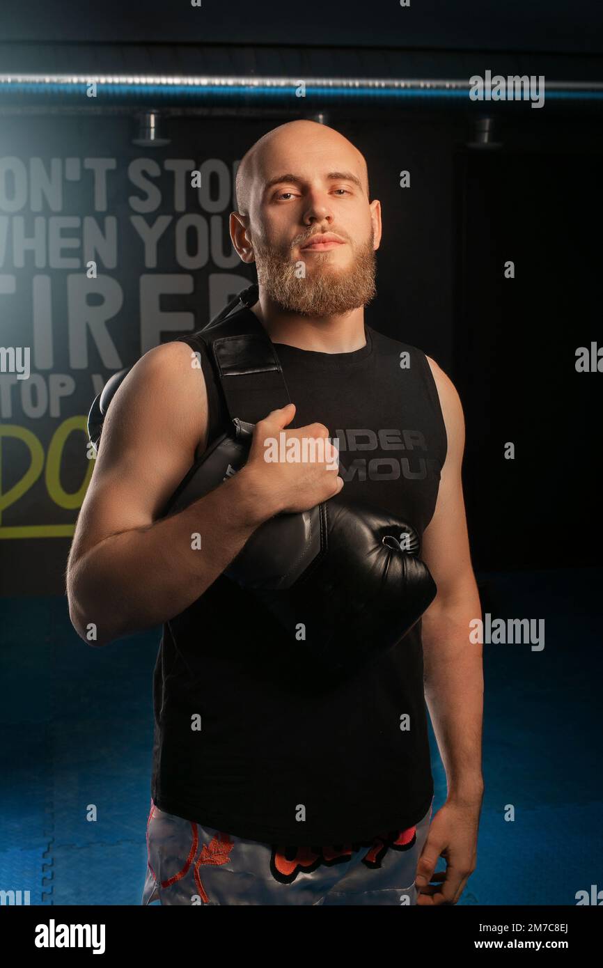bald men with a beard hold boxing gloves. strong view Stock Photo - Alamy