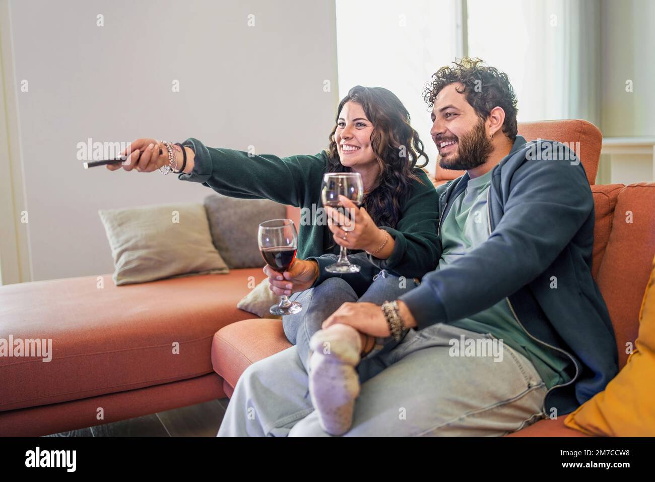 Loving couple drinking wine and watching tv sitting on the couch and ...