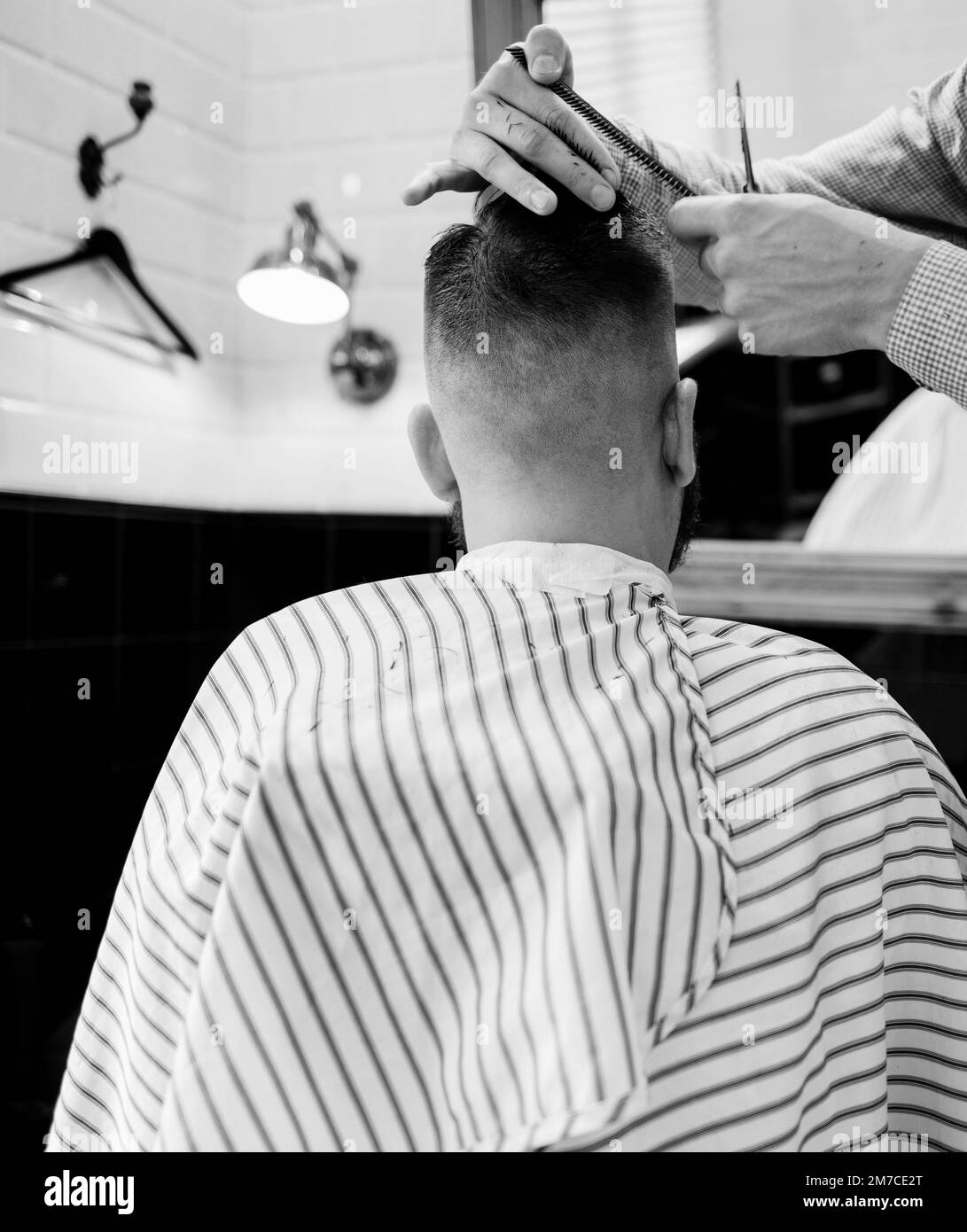 barber cuts the client's scissors in the salon. a man is sitting in a ...