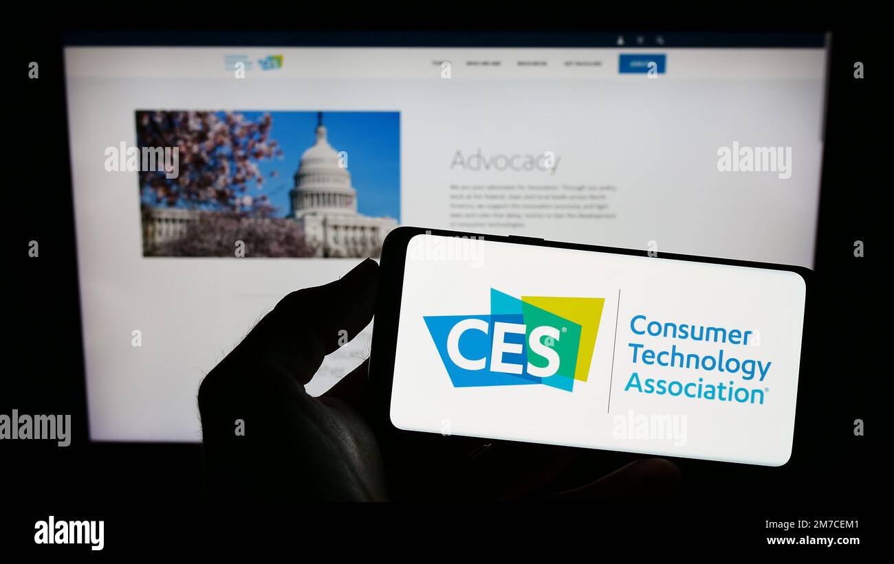 Person holding mobile phone with logo of American Consumer Technology ...