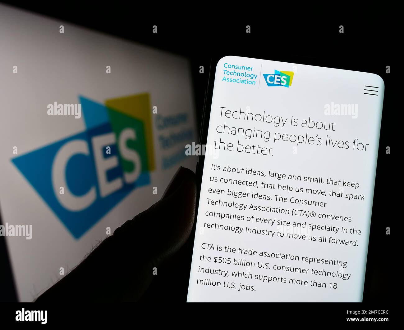 Person holding cellphone with webpage of US Consumer Technology Association (CTA) on screen in ...