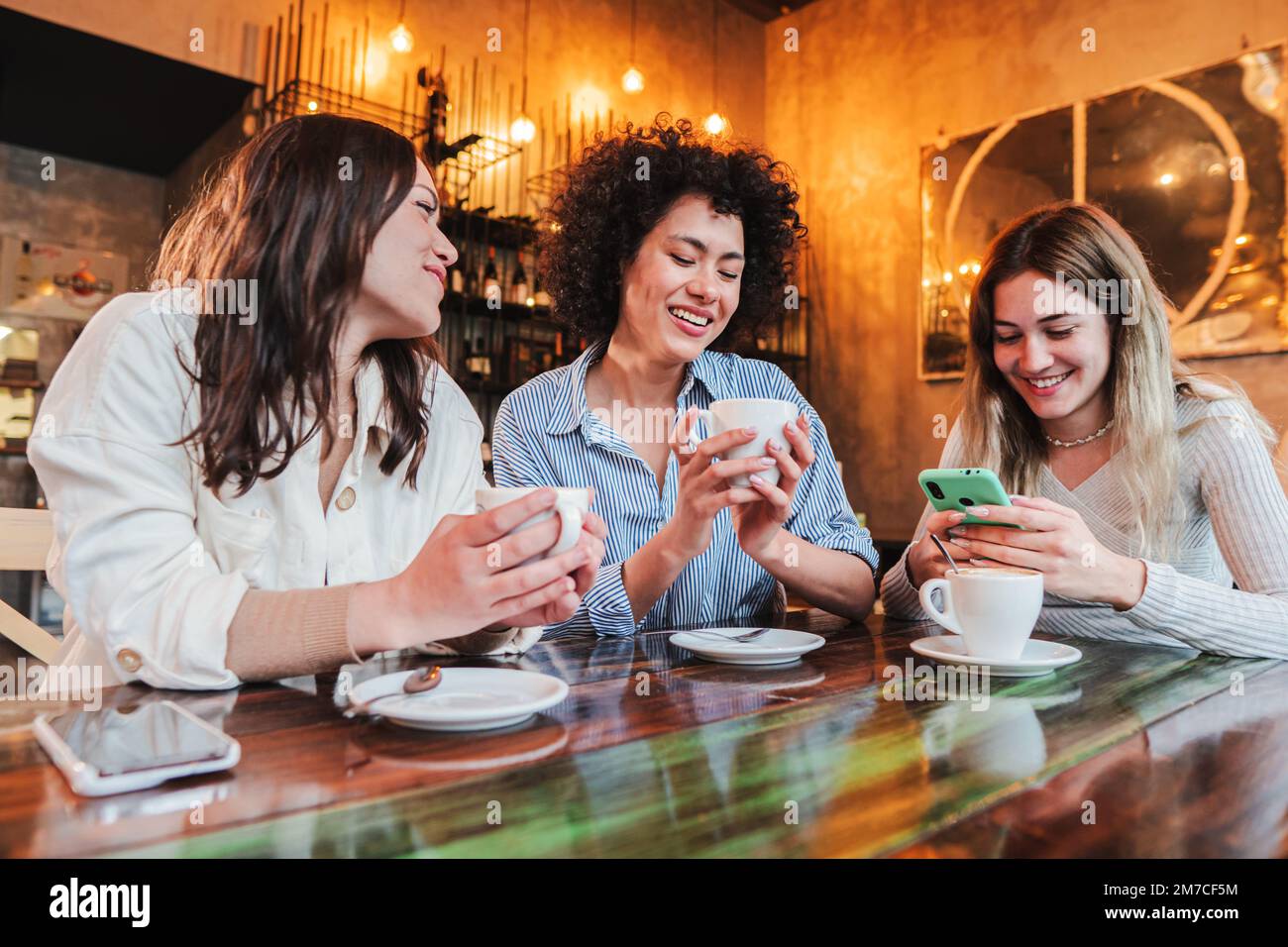 Group of three young females smiling and taking a coffee in a ...