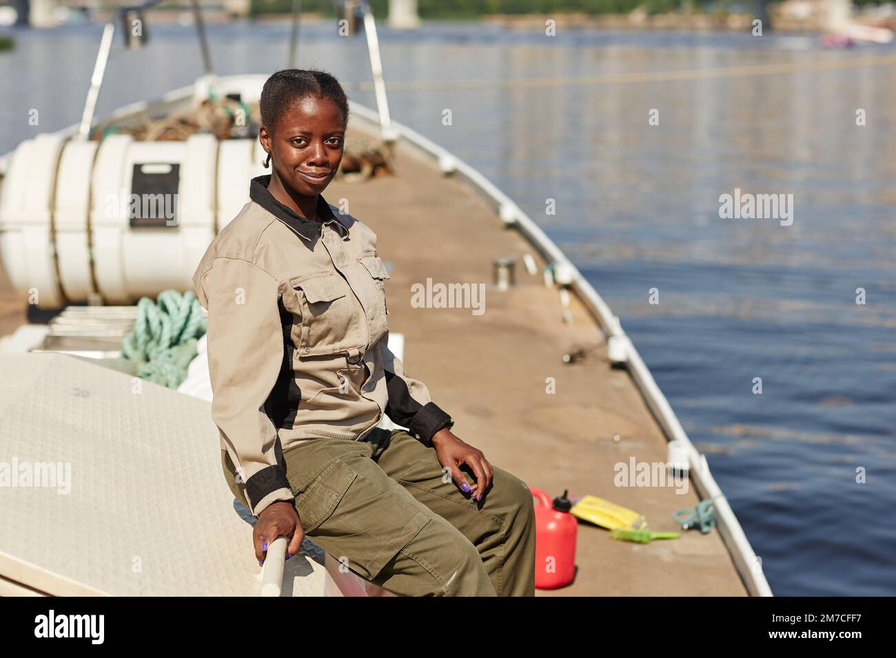 Portrait of black young woman sailing boat solo and looking at camera ...