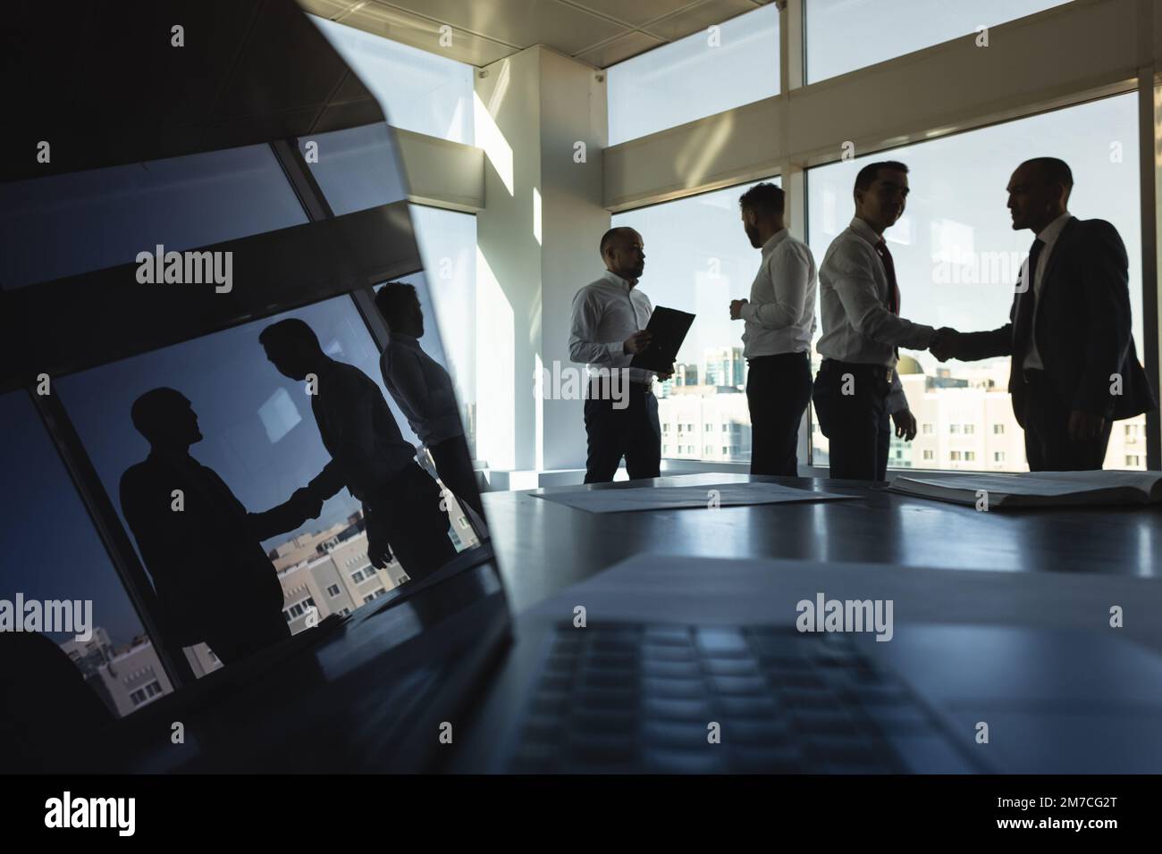 Silhouettes of people standing near a panoramic window in a modern ...