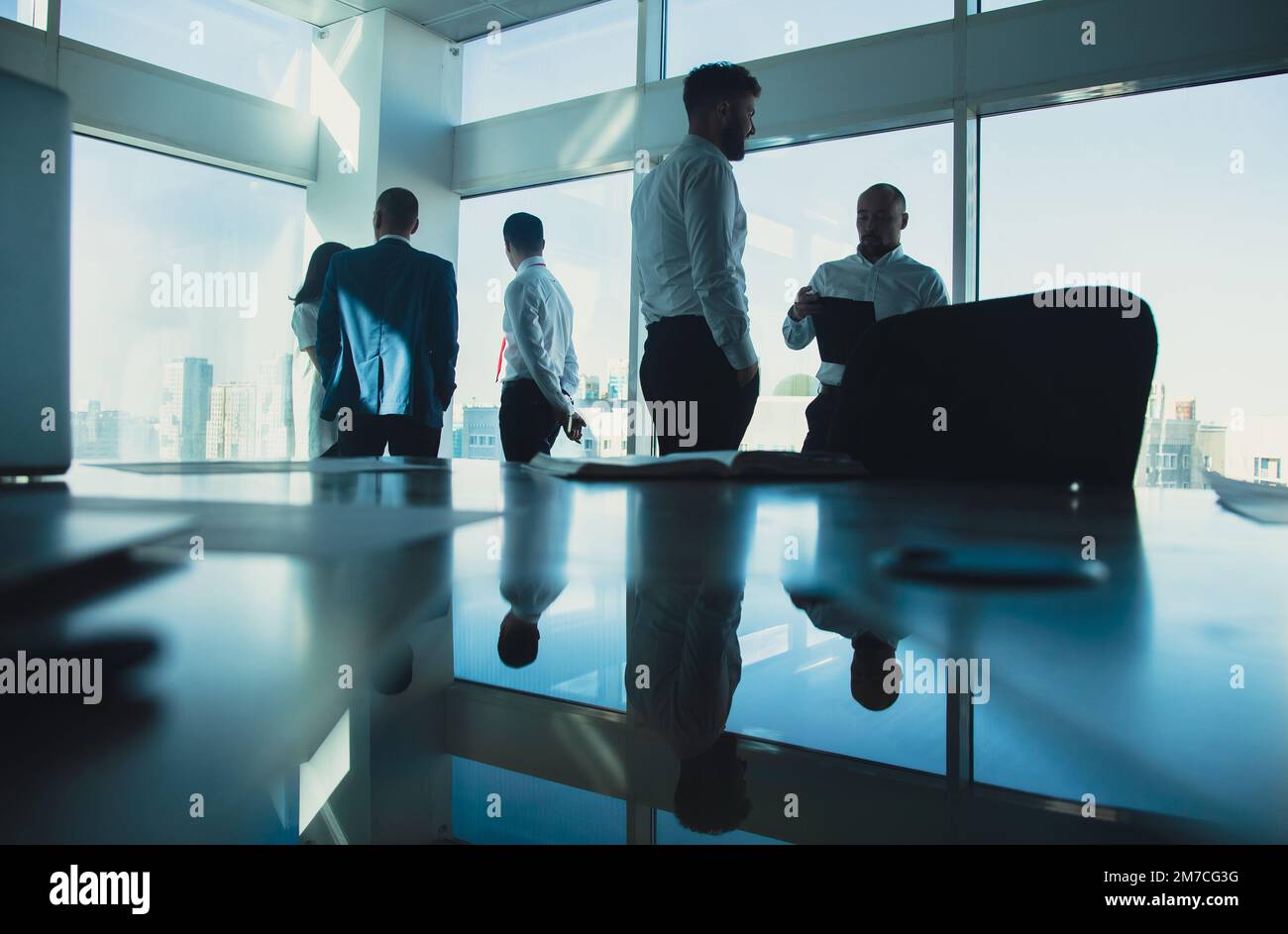 Silhouettes of people standing near a panoramic window in a modern ...
