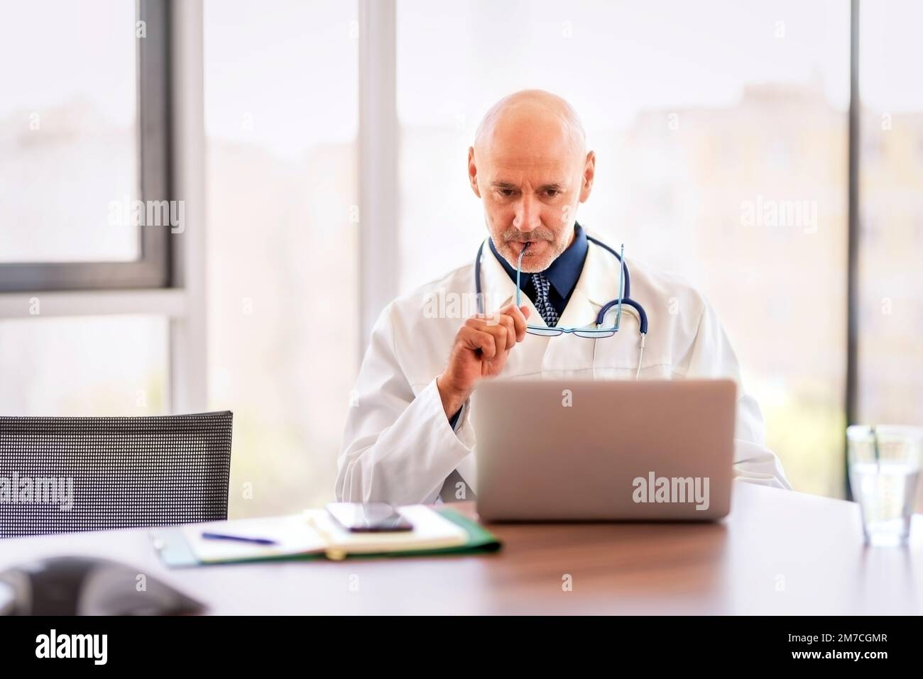 Shot of a mature doctor sitting alone in his clinic and looking ...